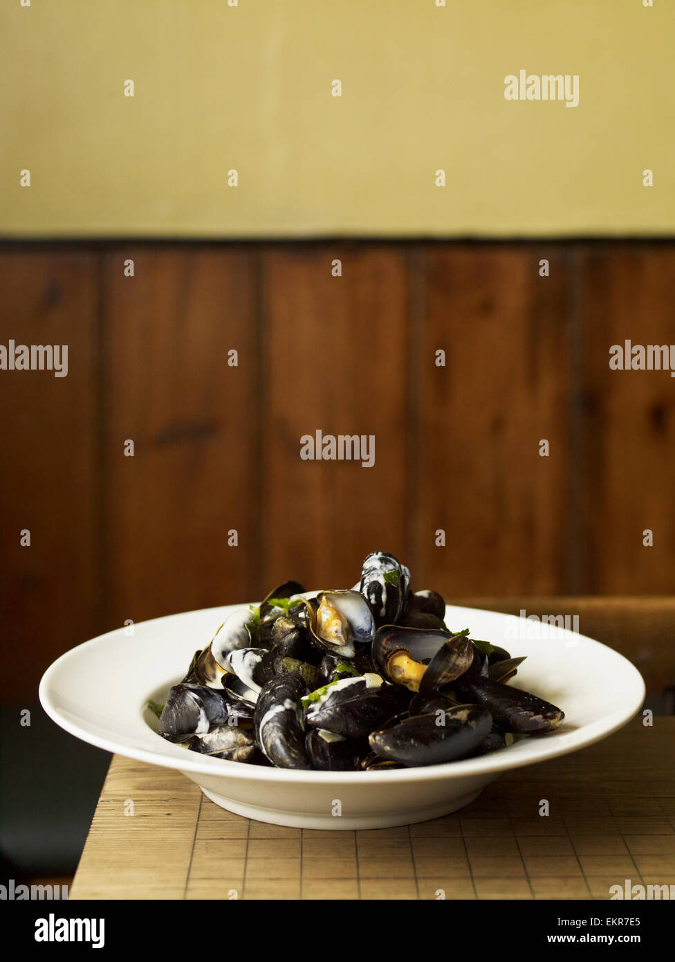 A traditional dish of steamed mussels, seafood on a white plate. Pub ...