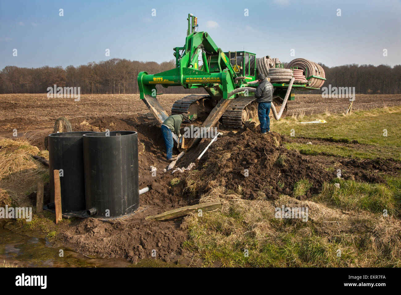Contractors working with drainage trencher / tile plow on farmland ...