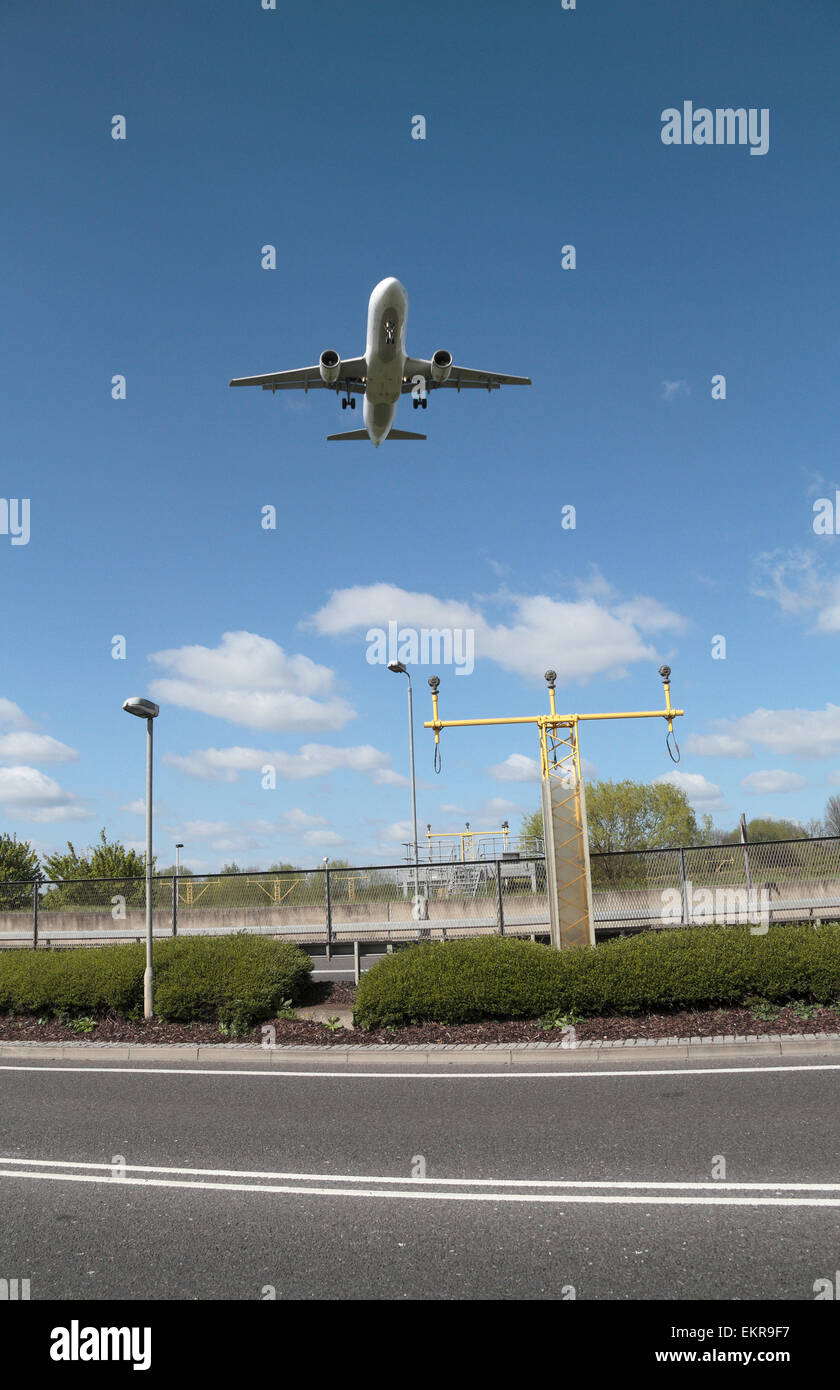 Twin engined plane passing over landing lights and over airport road ...