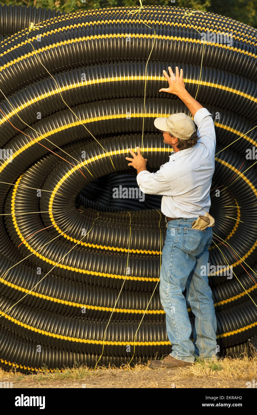 A farmer inspects a role of tubing; United States of America Stock ...