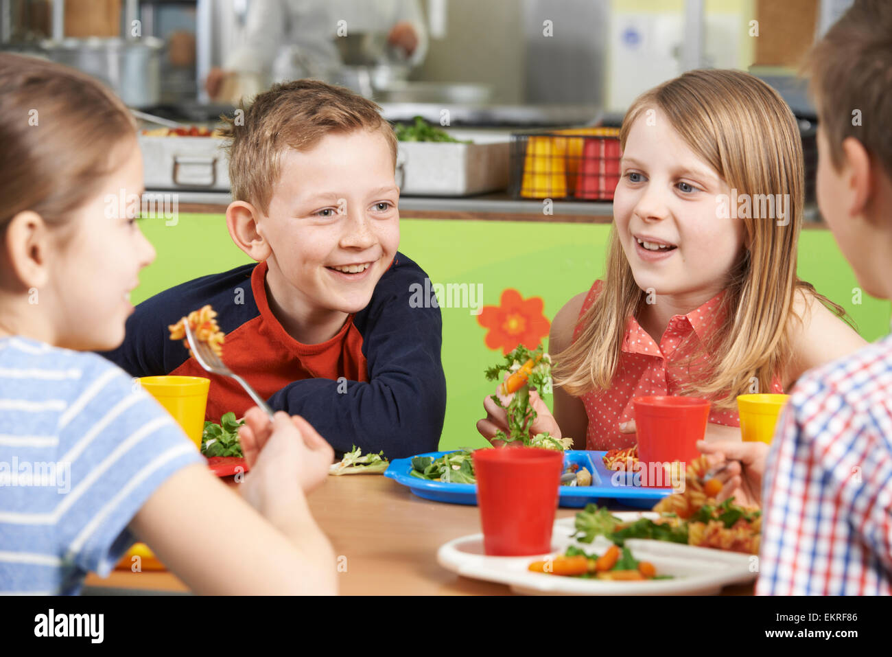Group Of Pupils Sitting At Table In School Cafeteria Eating Lunch Stock ...