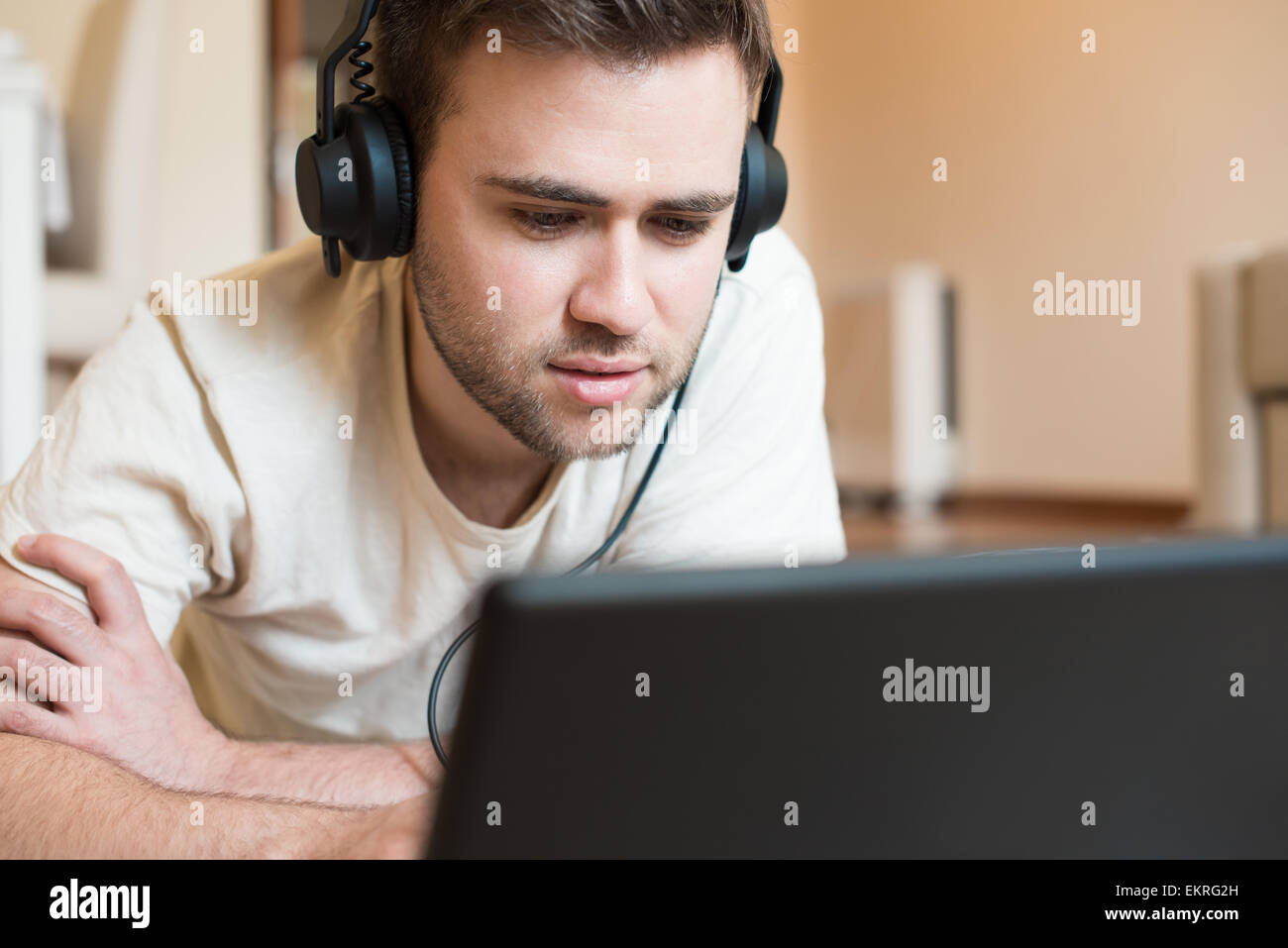 Man lying on the floor using headphones on laptop Stock Photo - Alamy