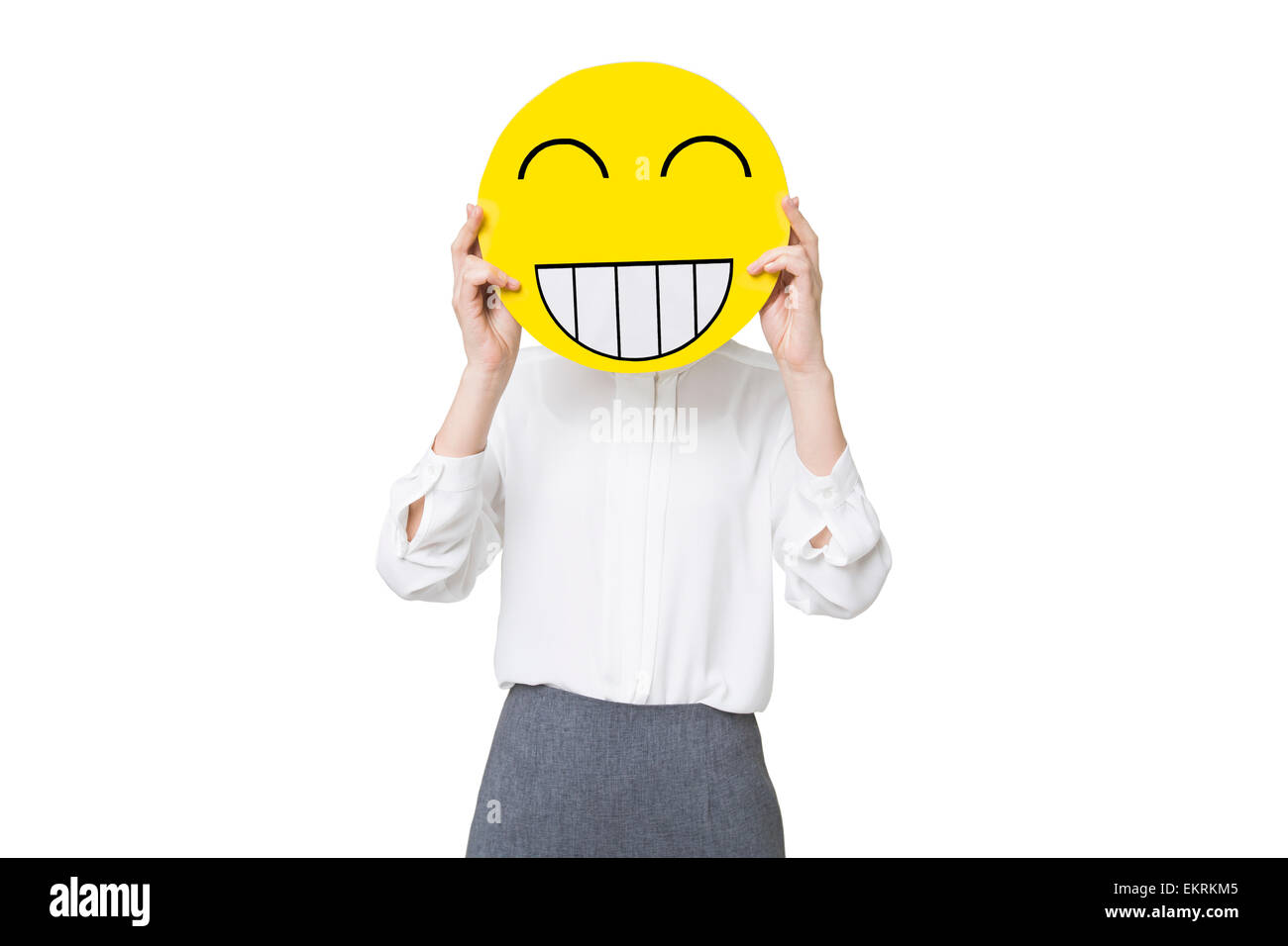 Young businesswoman holding a happy emoticon face in front of her face ...