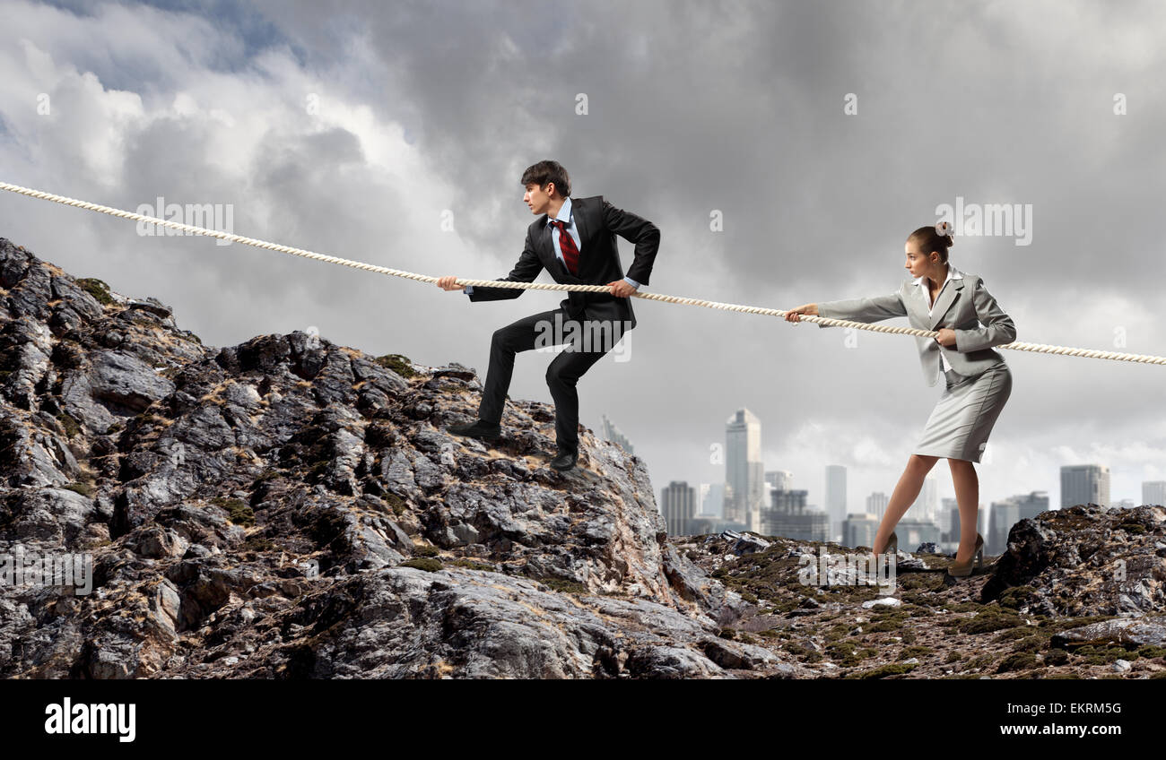 Two businessmen pulling rope atop of mountain Stock Photo - Alamy