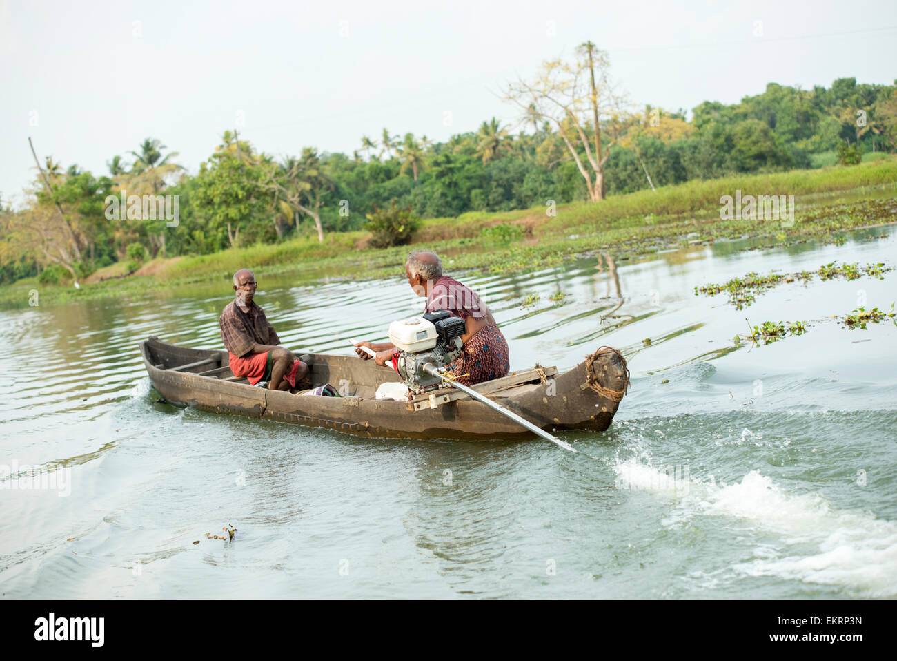 Two men in a motor boat on the Backwaters of Kumarakom, Kerala India ...