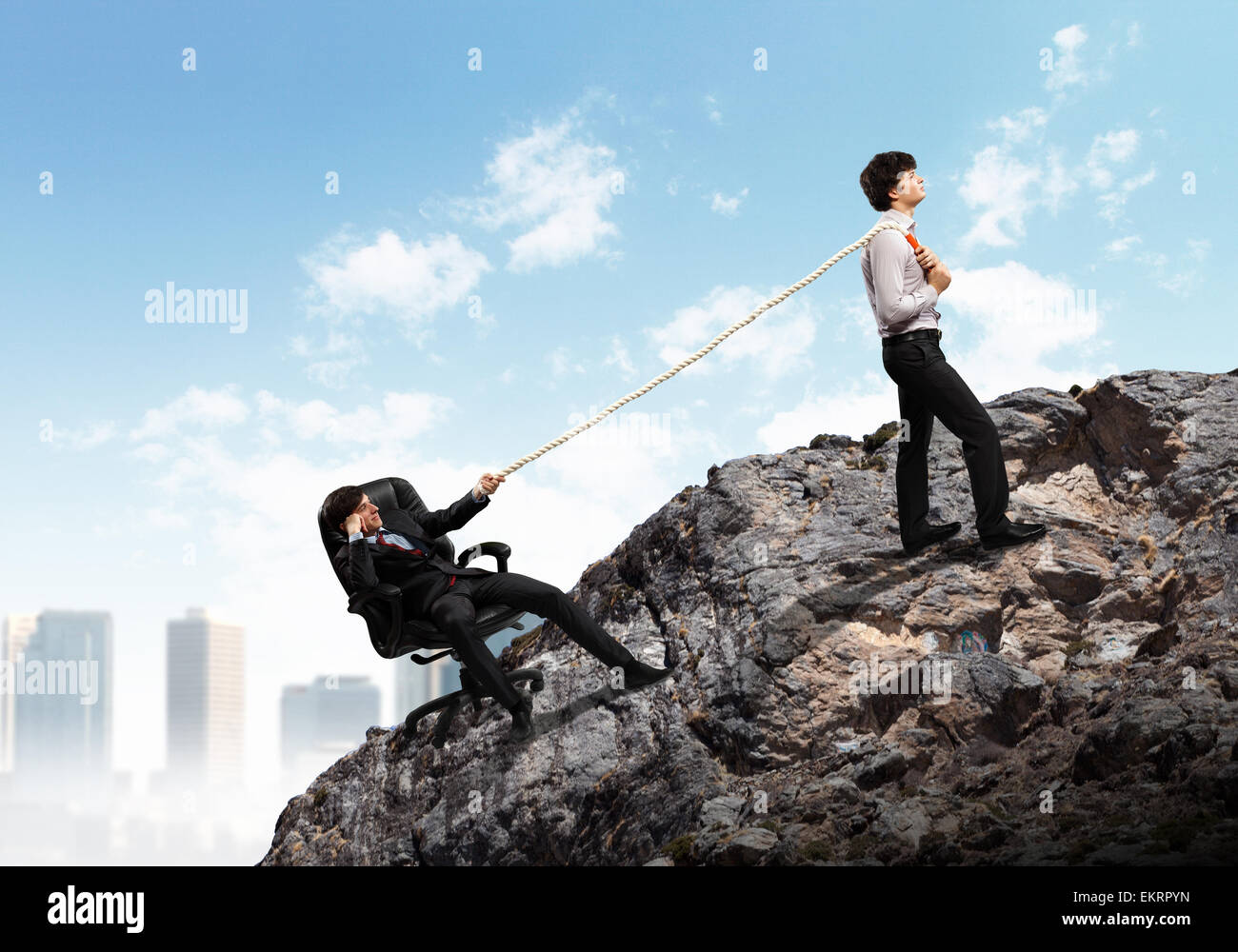 Two businessmen pulling rope atop of mountain Stock Photo - Alamy