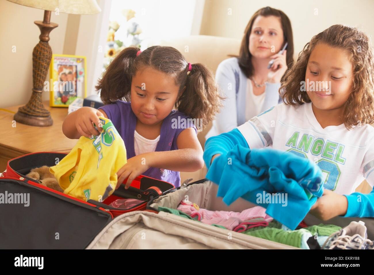 Two Girls Packing Their Suitcases With Their Mother On The Phone Stock ...