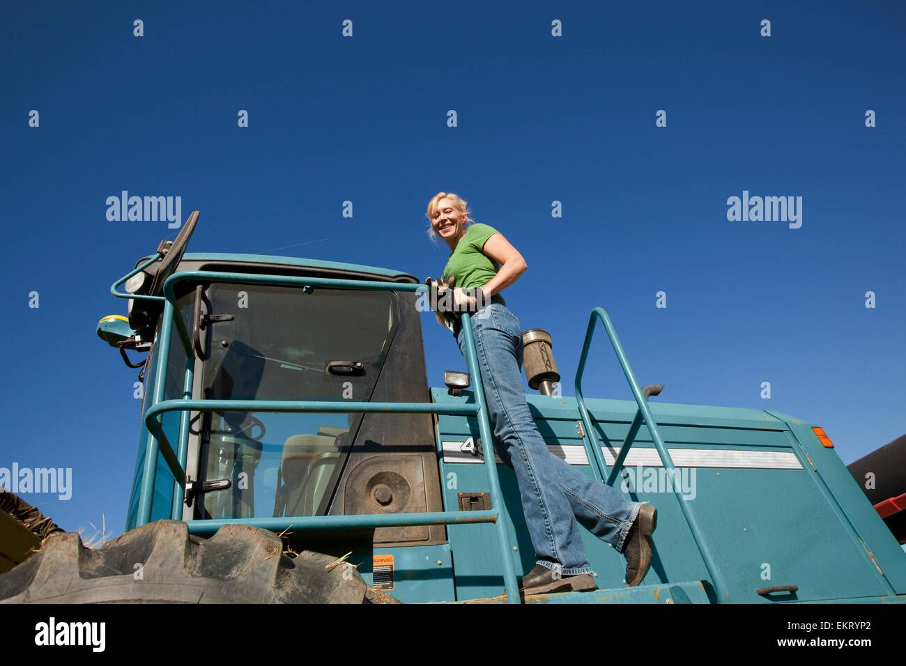 Female Farmer Standing On Combine Tractor; Three Hills, Alberta, Canada ...