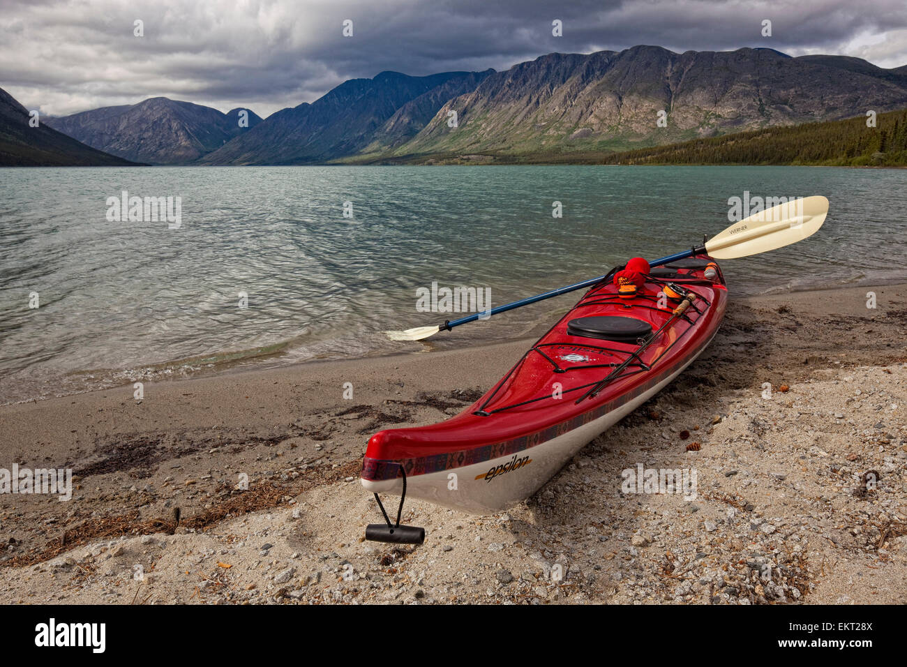 Kayak sitting on the shoreline of Kusawa Lake with the setting sunlight ...
