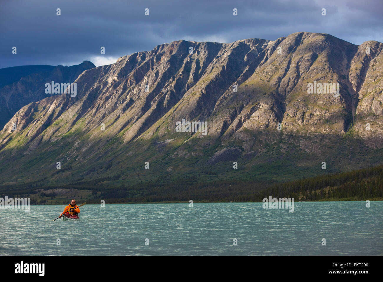 Kayaker on Kusawa Lake with the setting sun hitting the mountains ...