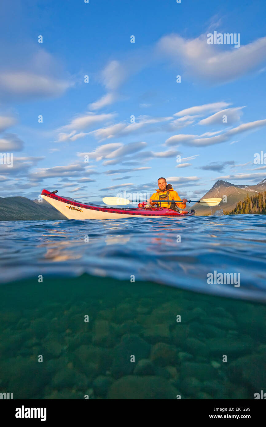 Kayaker on Kusawa Lake at sunset, shot half above and half below water ...