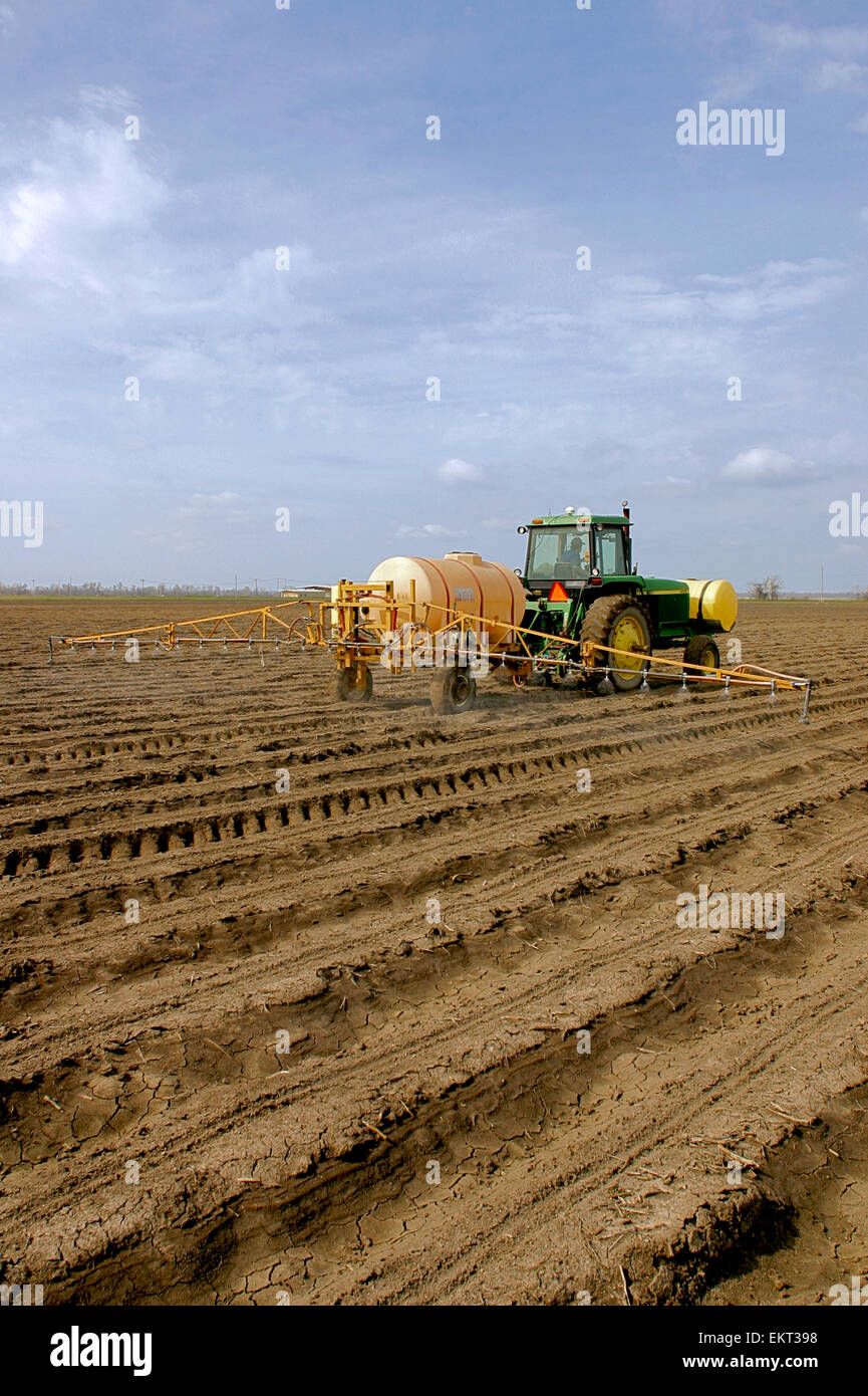 A tractor equipped with a sprayer applies a pre-plant herbicide to a ...