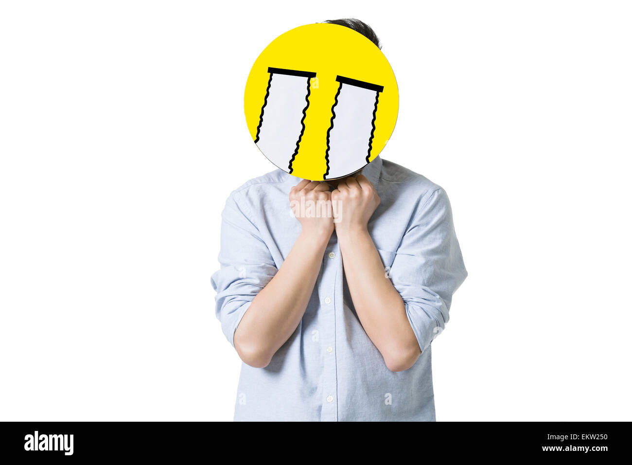 Young man with a crying emoticon face in front of his face Stock Photo ...