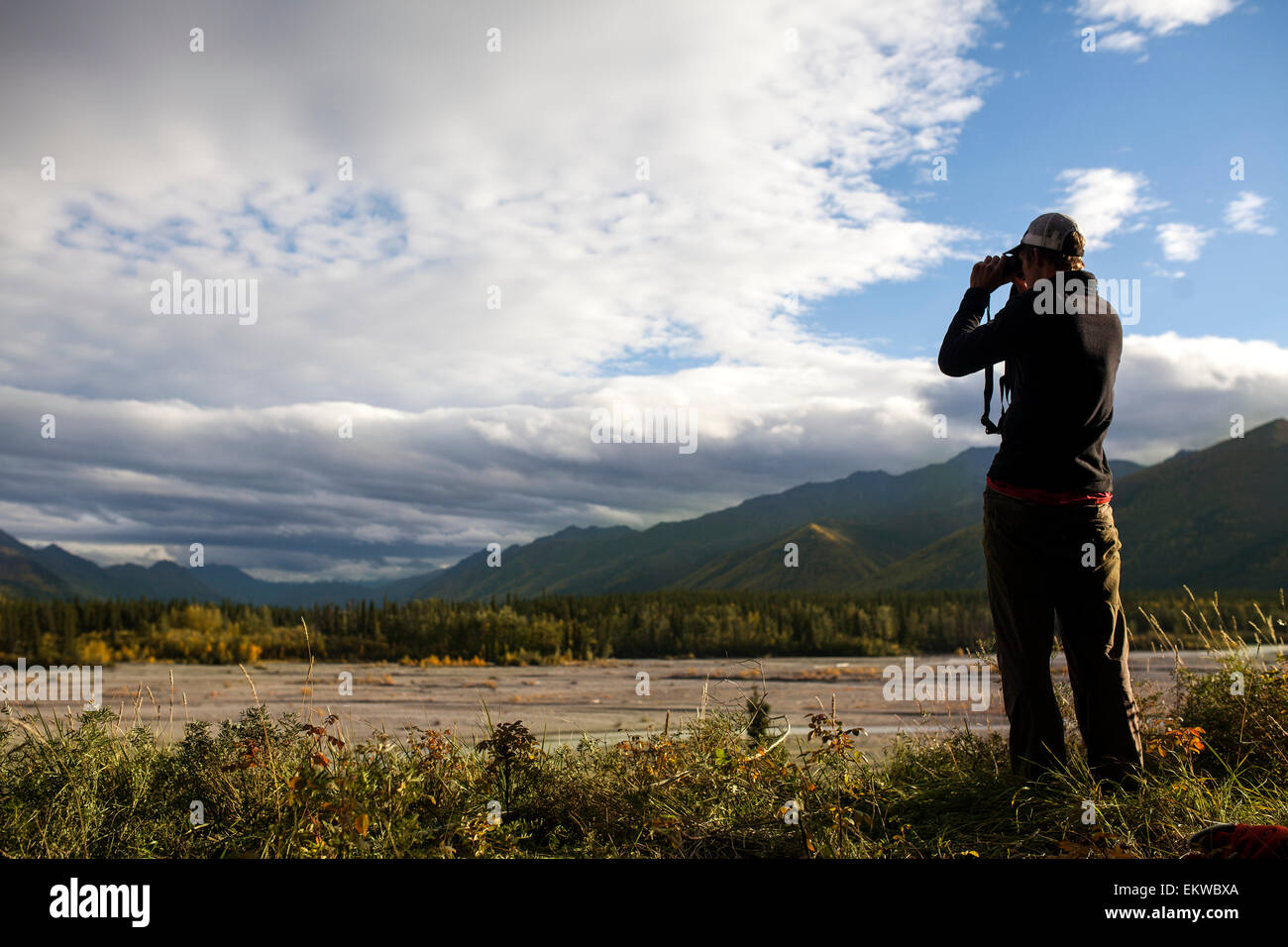 Man watches a braided riverbed with binoculars while hunting near Tok ...