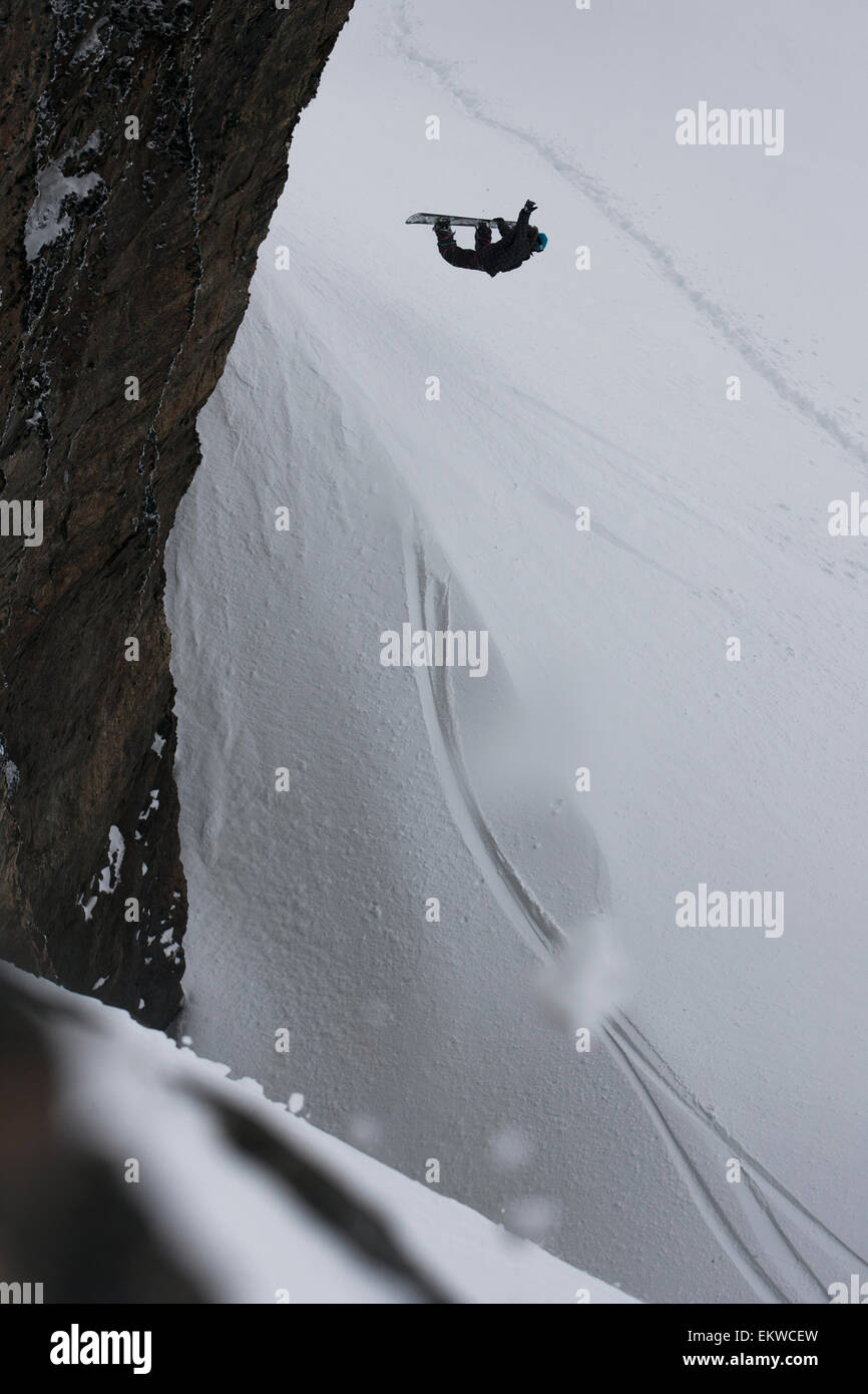 Professional snowboarder making an extreme jump of a vertical wall near ...