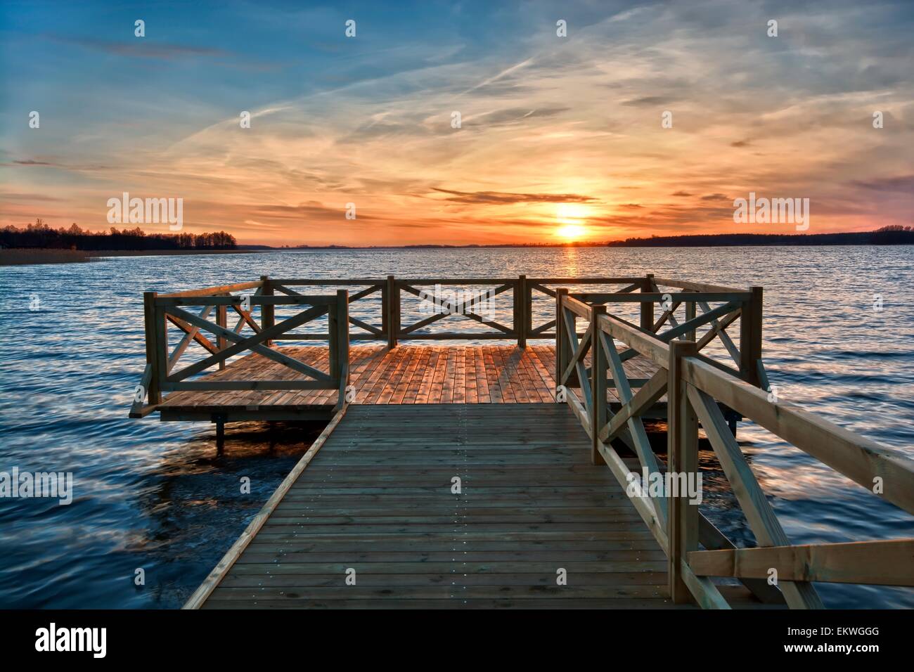 View of wooden jetty on beautiful lake during sunset, Mazury, Poland ...
