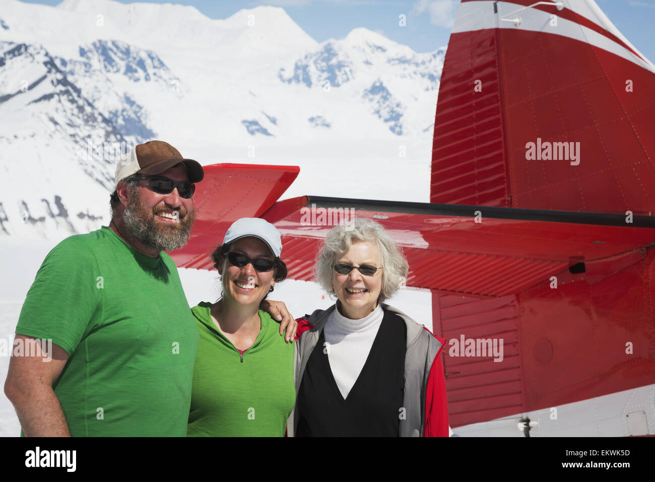 A happy family posing with their flightseeing plane on the Ruth Glacier ...