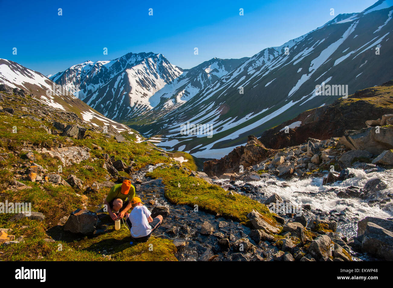 Father and son fill their water bottle near the summit of Crow Creek ...