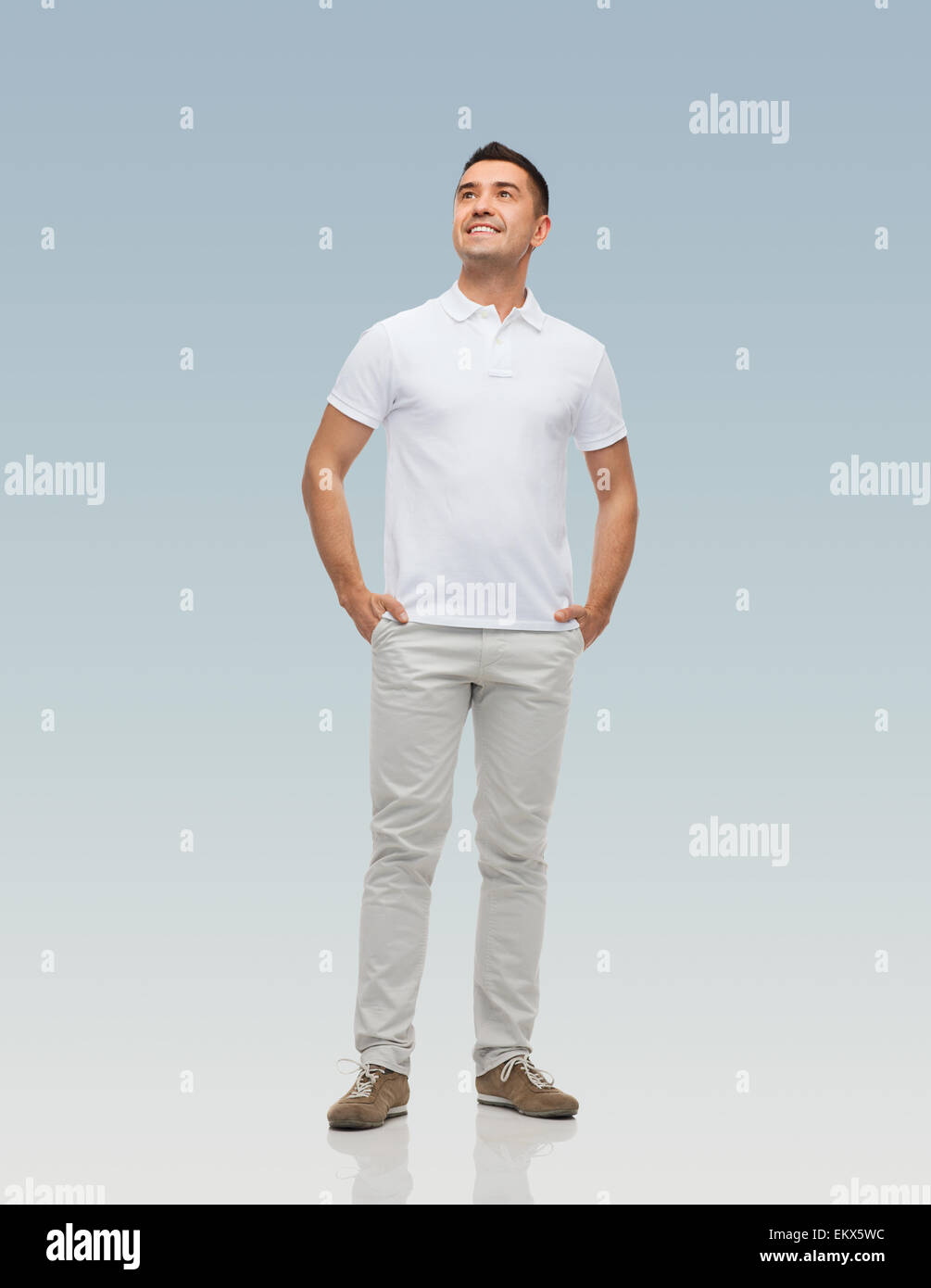 smiling man with hands in pockets looking up Stock Photo - Alamy