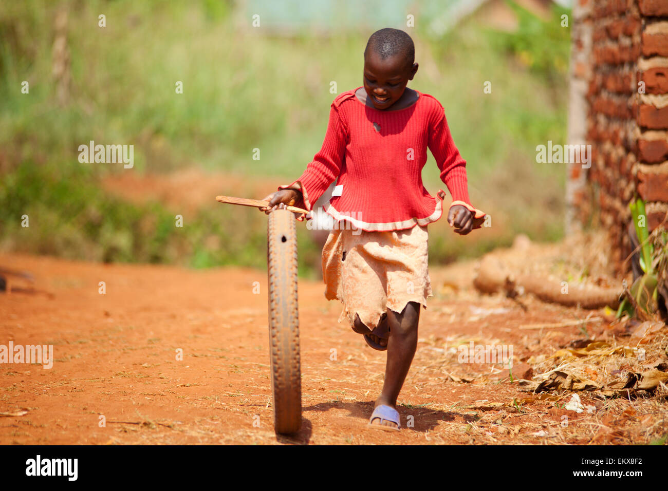 A Boys Runs Alongside A Rolling Tire; Kampala Uganda Africa Stock Photo ...