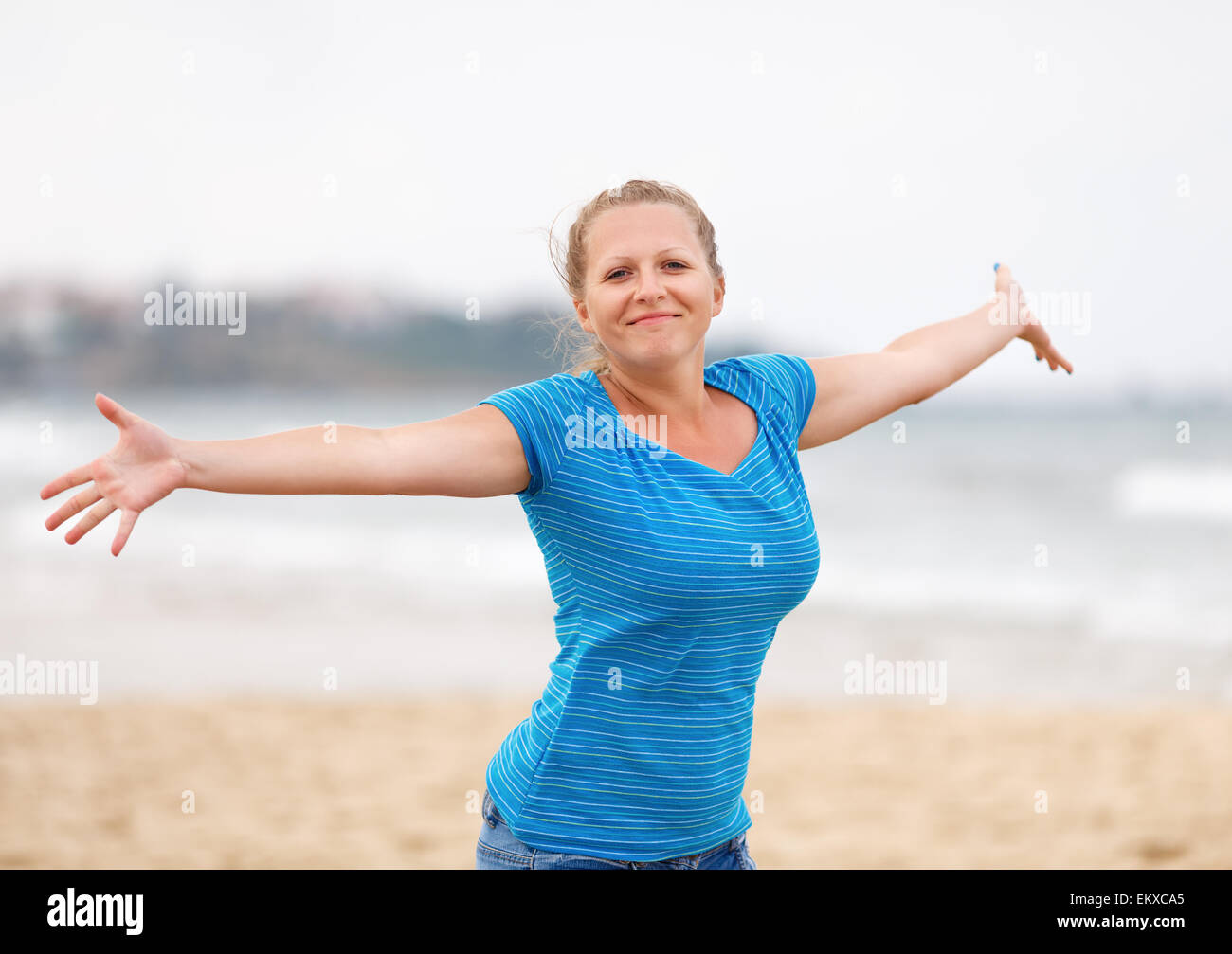 Beautiful smiling young woman posing arms to the side and enjoy the ...