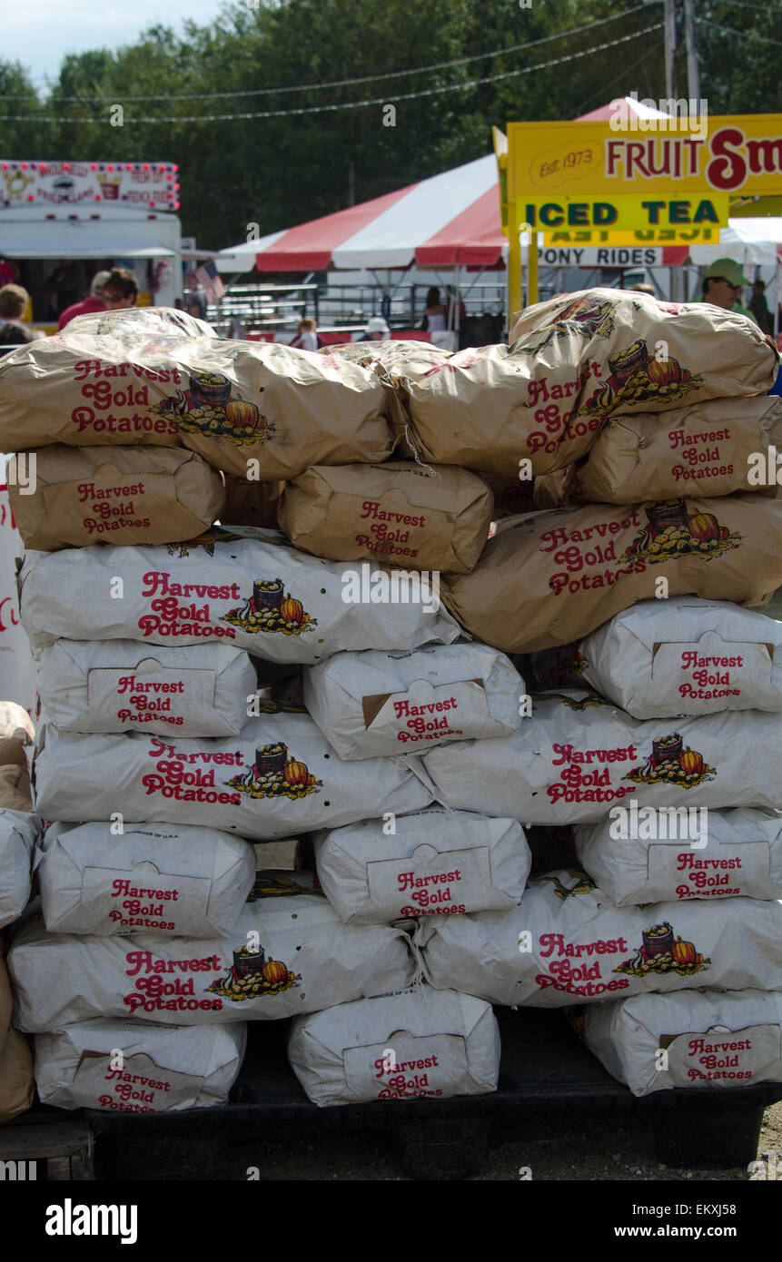 Pallets piled with bags of potatoes behind a french fry vendor's stall ...