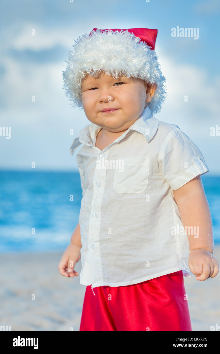 Little Santa boy on the beach Stock Photo - Alamy