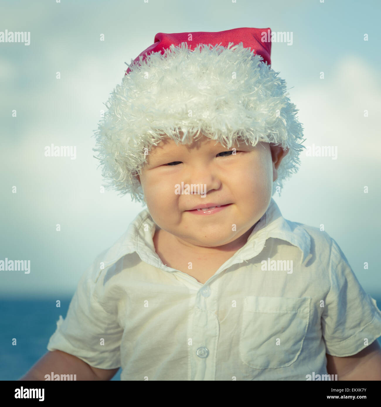 Little Santa boy on the beach Stock Photo - Alamy