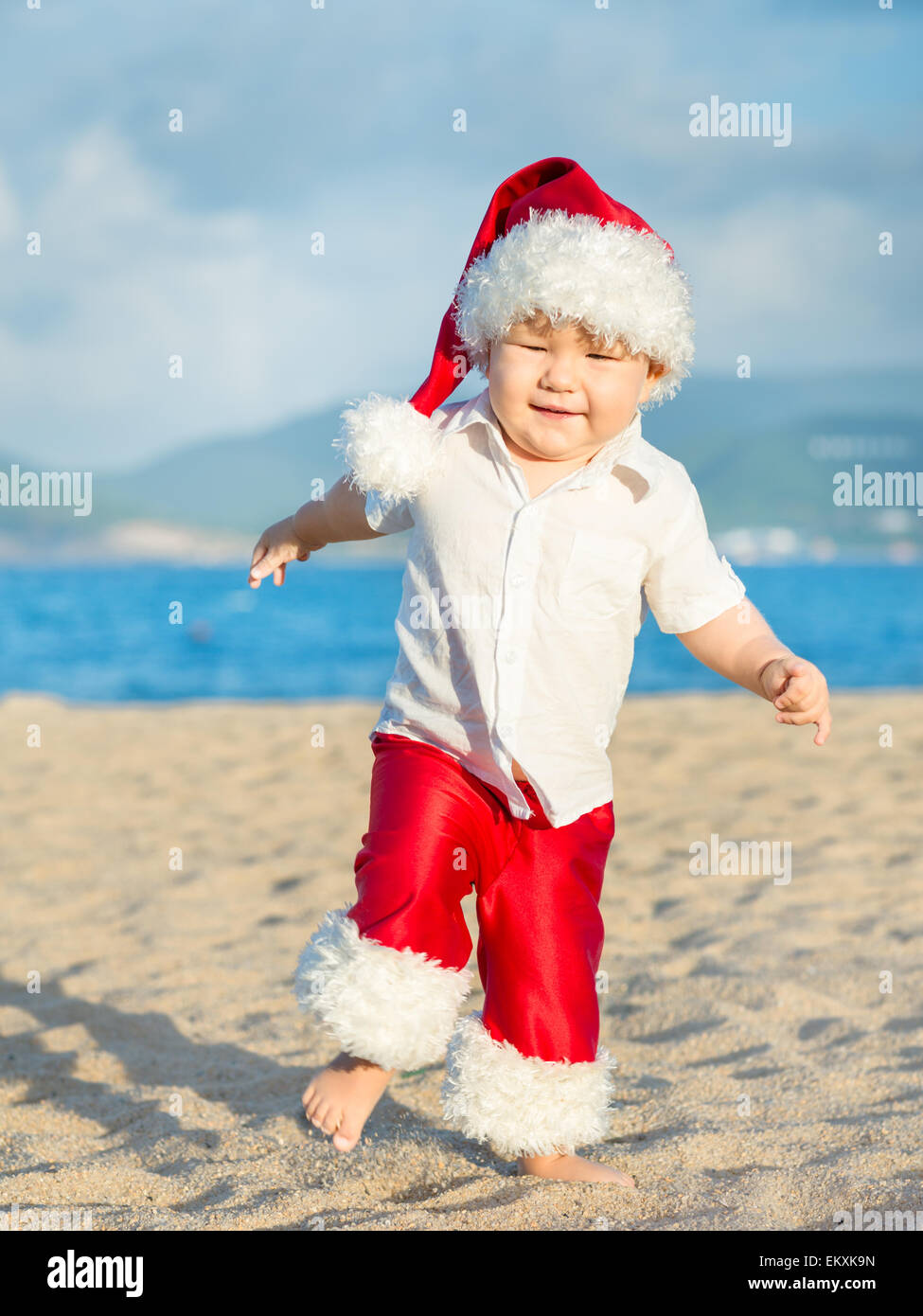 Little Santa boy on the beach Stock Photo - Alamy