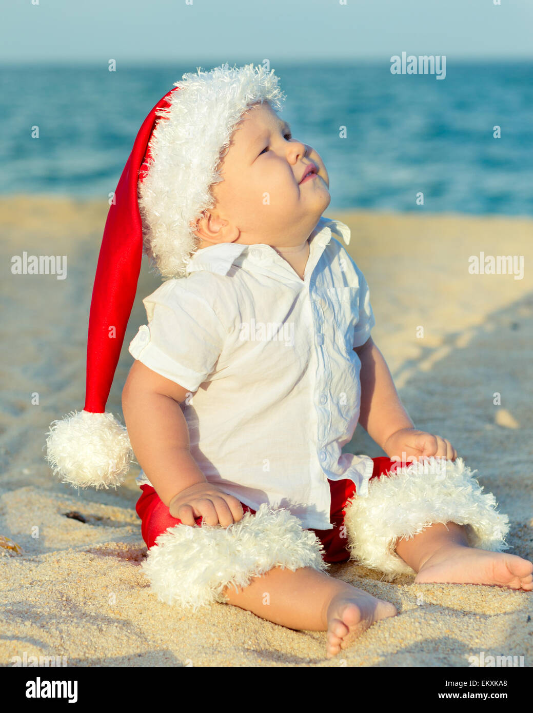 Little Santa boy on the beach Stock Photo - Alamy