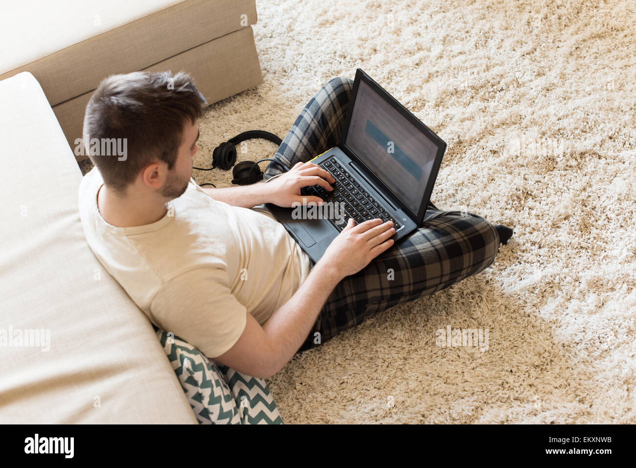 Man sitting on the floor typing on laptop - focus on laptop Stock Photo ...