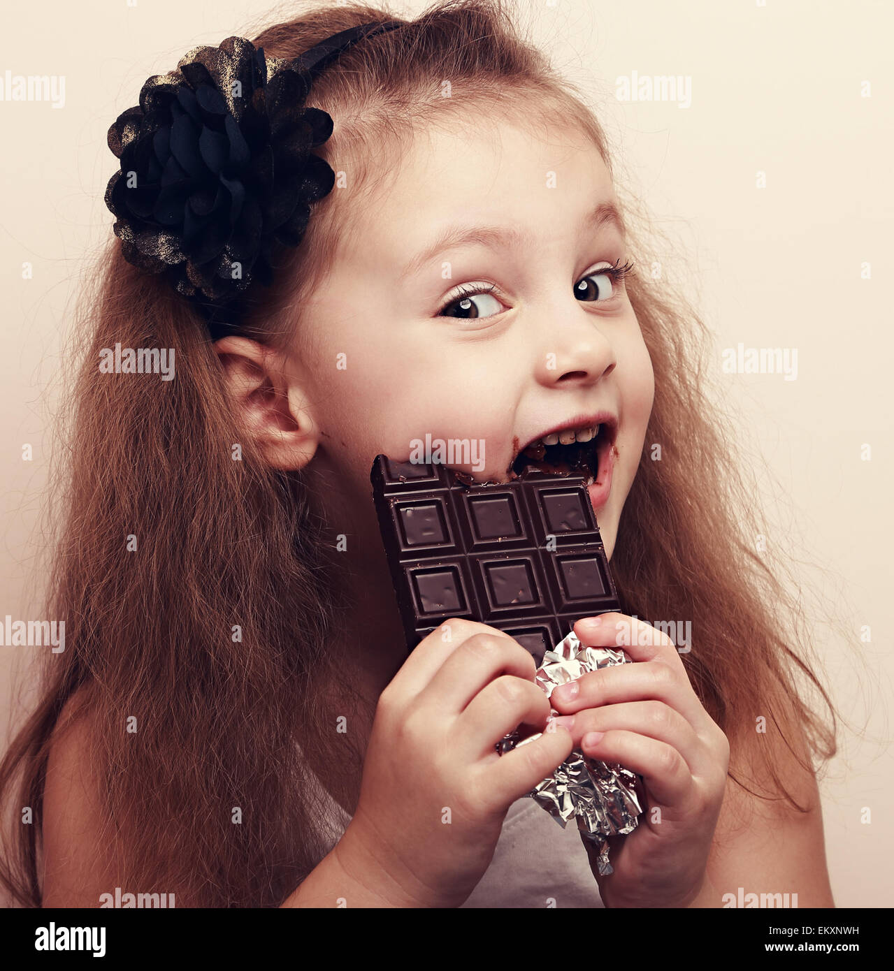 Happy cute beautiful kid girl biting sweet chocolate. Vintage closeup ...