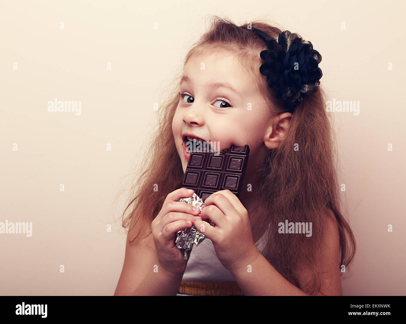 Happy smiling kid girl biting tasty chocolate with empty copy space ...