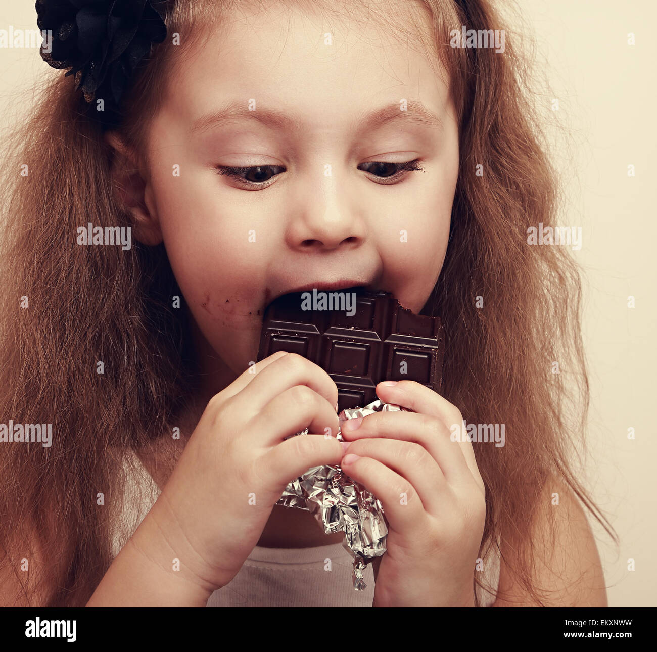 Happy expression kid girl biting dark chocolate. Closeup vantage ...