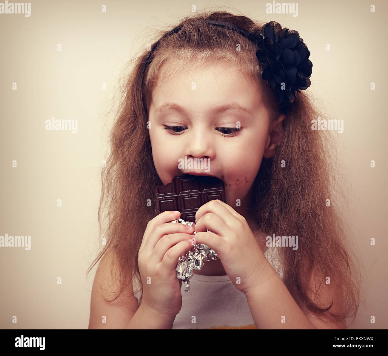 Fun happy kid girl eating dark chocolate. Closeup Vintage portrait ...