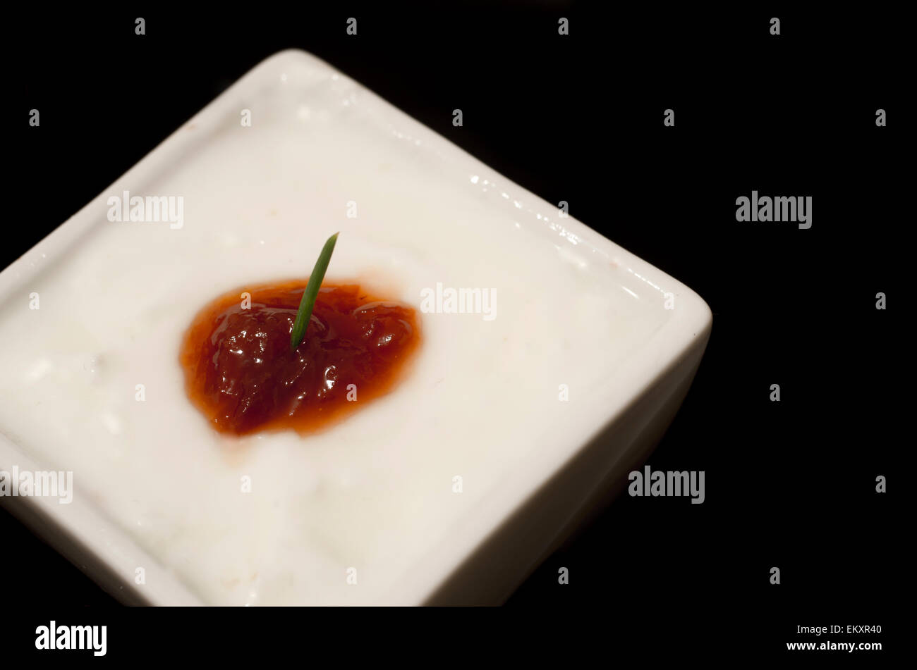 Yogurt with jam and pin leave on black background Stock Photo - Alamy