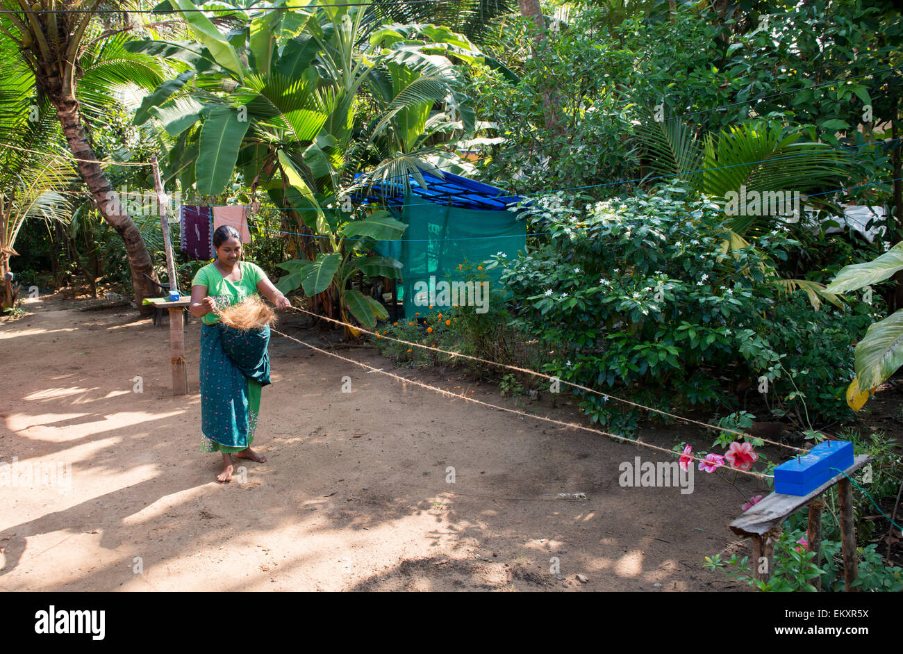 A young Indian woman demonstrates how to make string from coconut shell ...