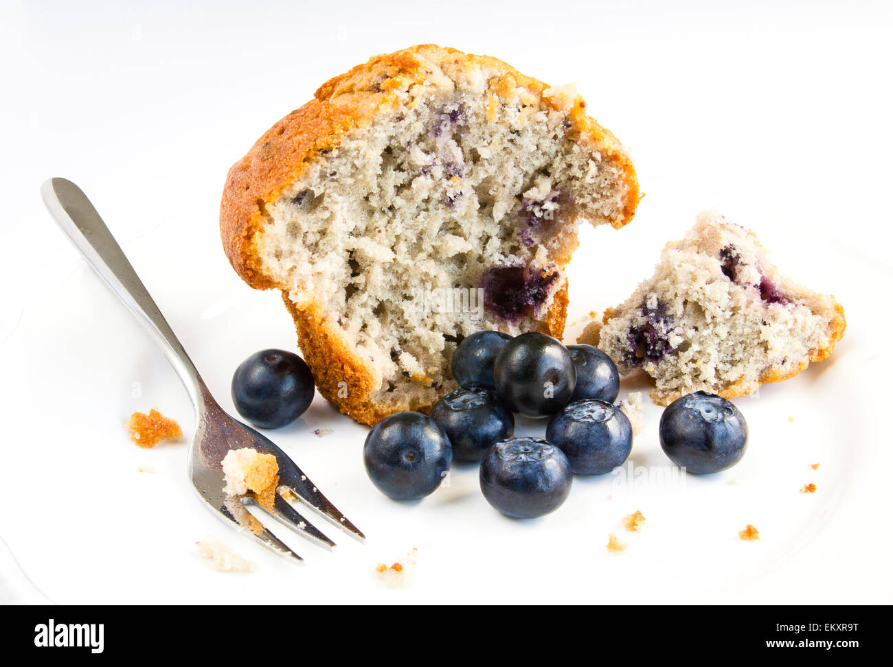 Open blueberry muffin with fresh blueberries and fork on white plate ...