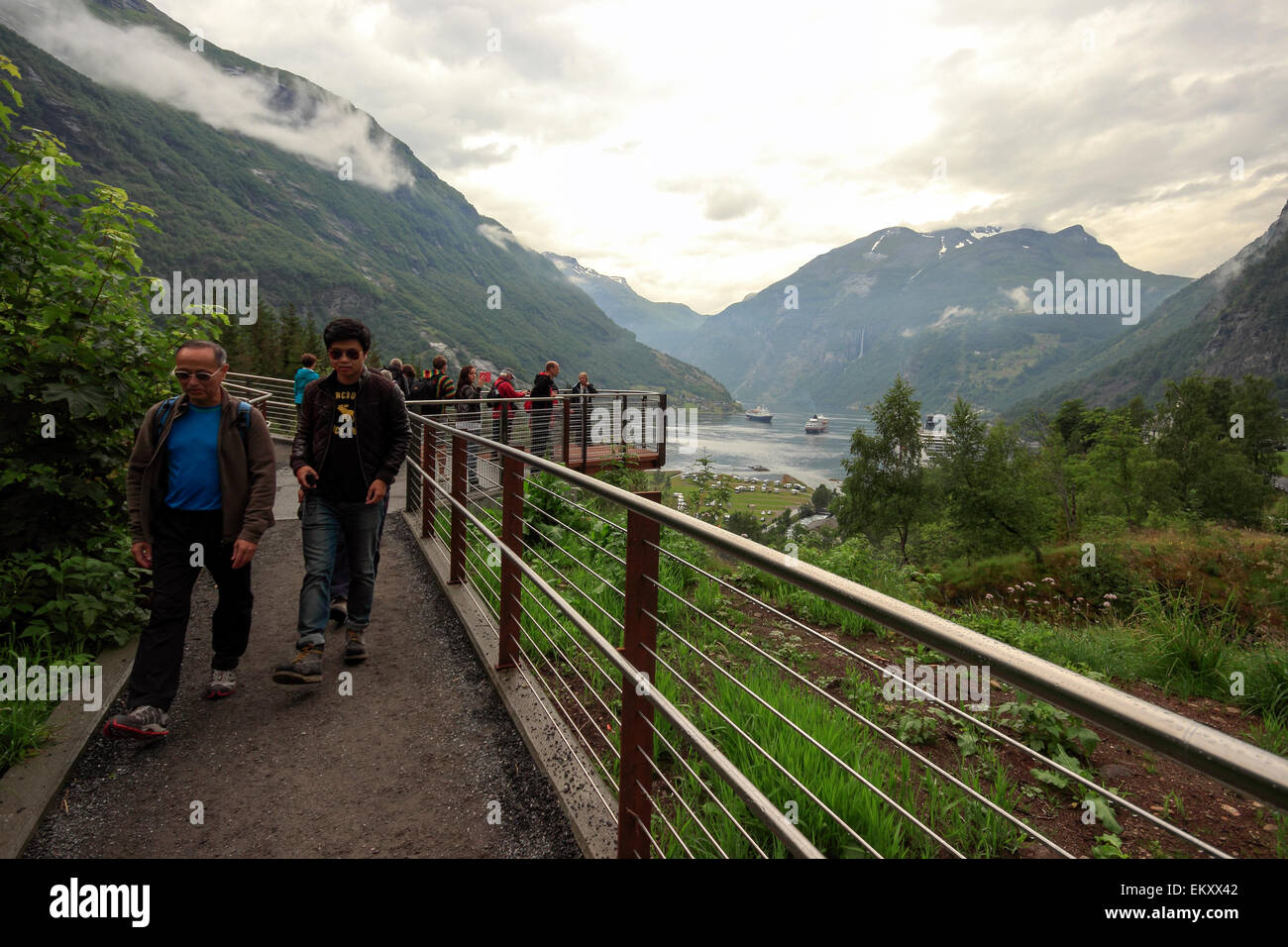 Tourists along a riverwalk, Geiranger, with a cruise ship on the ...
