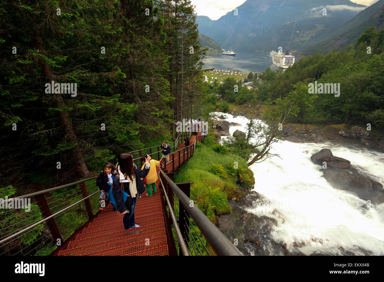 Tourists along a riverwalk, Geiranger, with a cruise ship on the ...