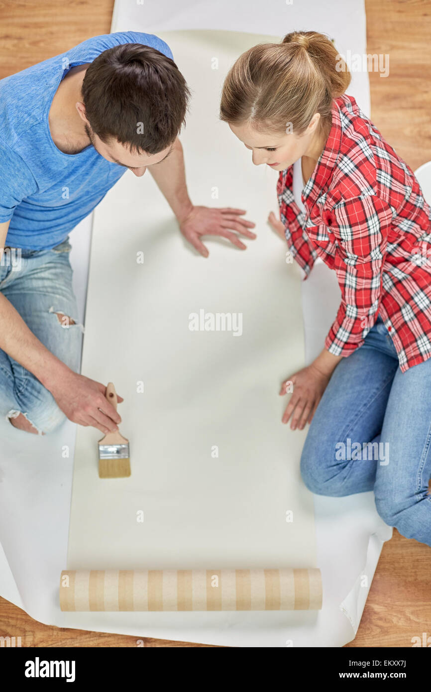 close up of couple smearing wallpaper with glue Stock Photo - Alamy