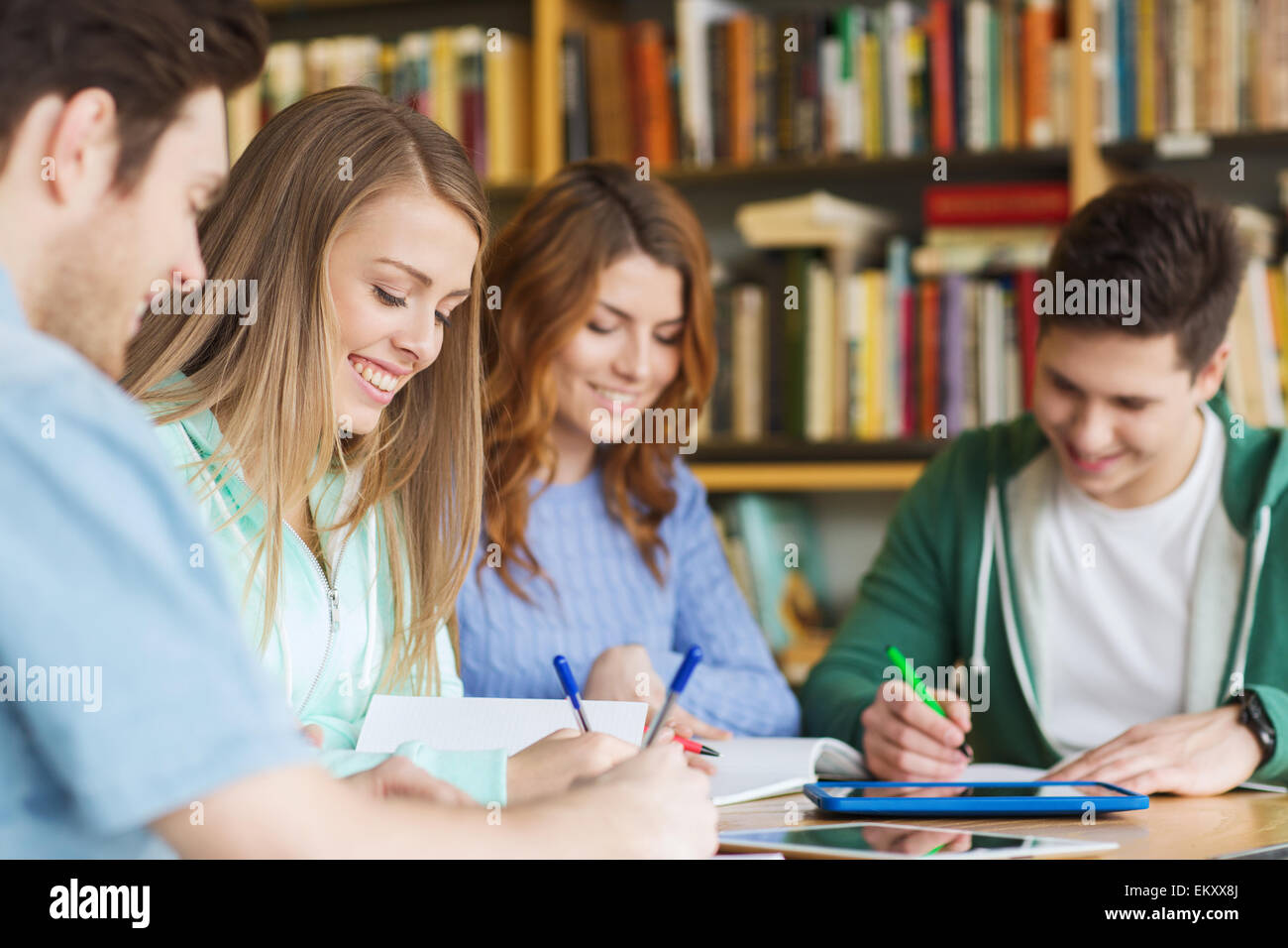 happy students writing to notebooks in library Stock Photo - Alamy