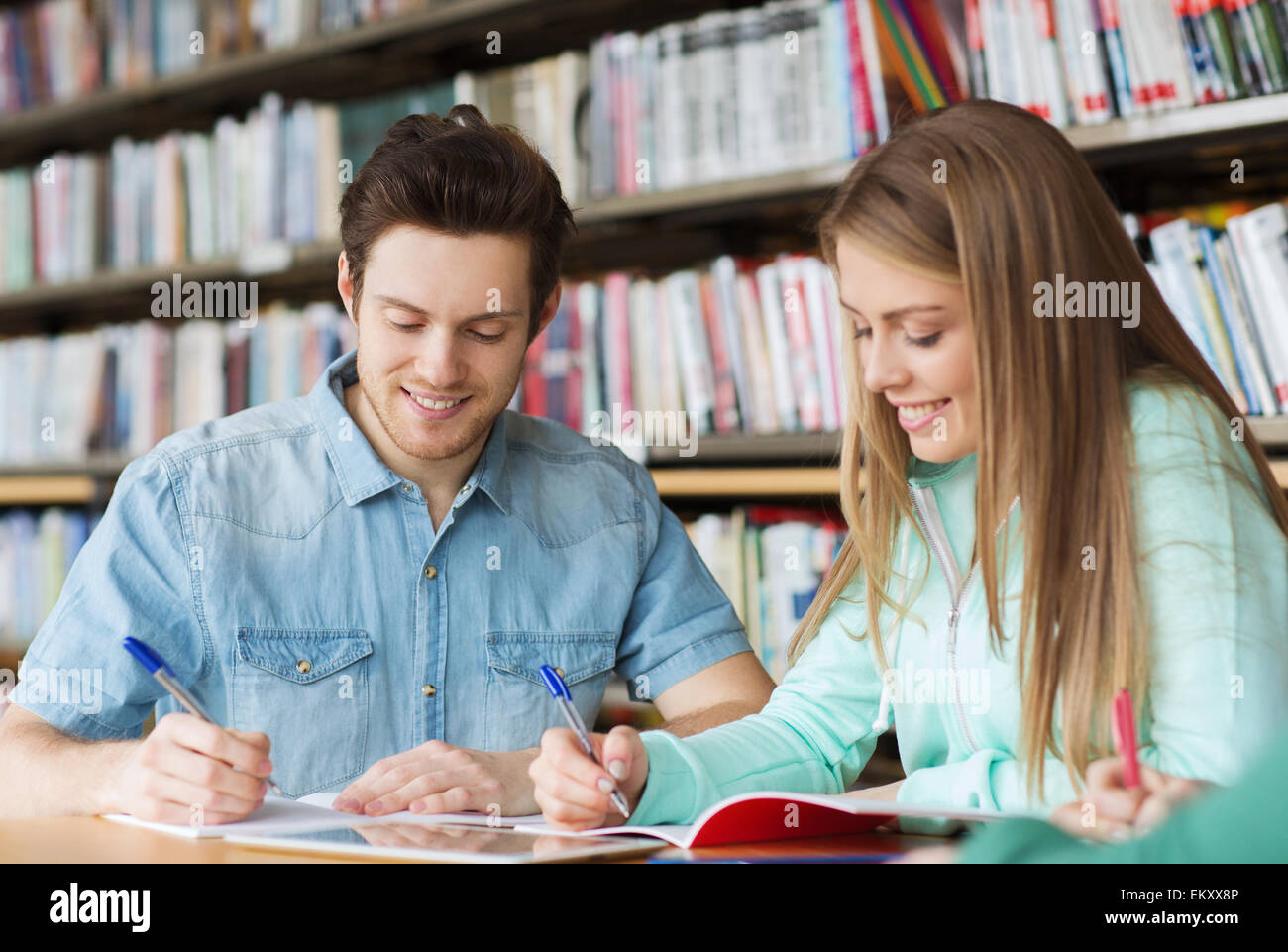 happy students writing to notebooks in library Stock Photo - Alamy