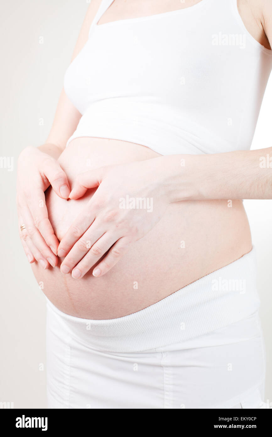 pregnant woman holding her belly arms Stock Photo - Alamy
