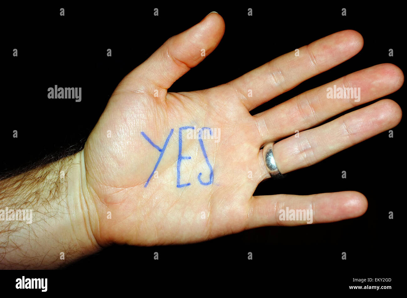 Yes written on a white man's hand photographed against a black ...