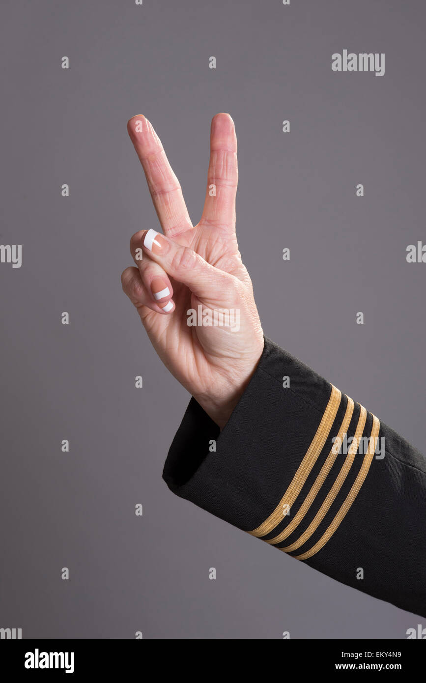 Airline officer making a gesture with her hand V sign Stock Photo - Alamy