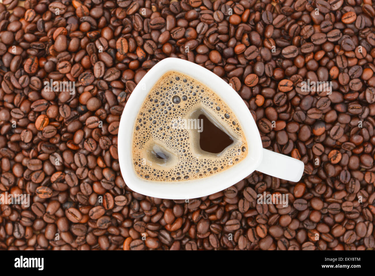 Unique triangle shaped cup of black coffee on coffee beans background ...