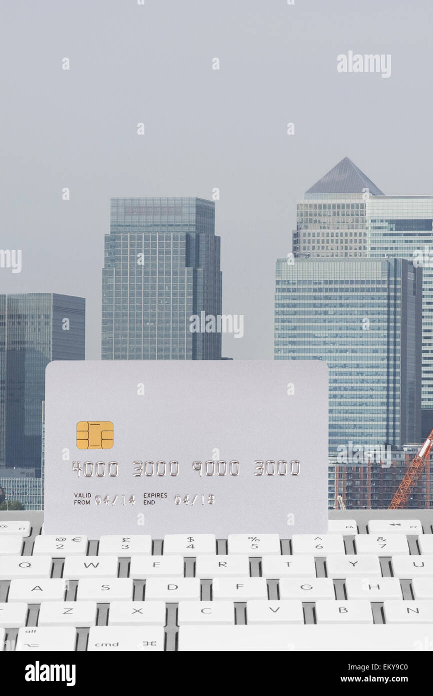 Credit card on a computer keyboard with Canary Wharf Financial district ...