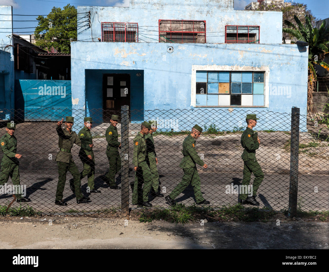Cuban soldiers march past an old brightly coloured derelict building in ...