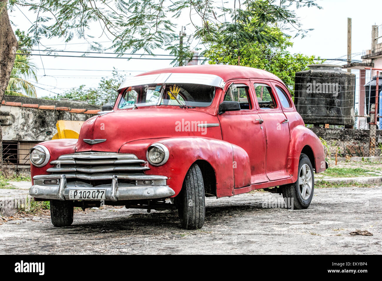 Old American red car parked on a dusty road in a village in a remote ...